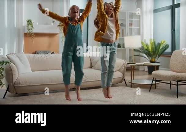 Two happy Caucasian sisters children kids singing song jumping dancing ...