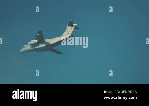 Large military cargo plane flying through a hazy blue sky and ...