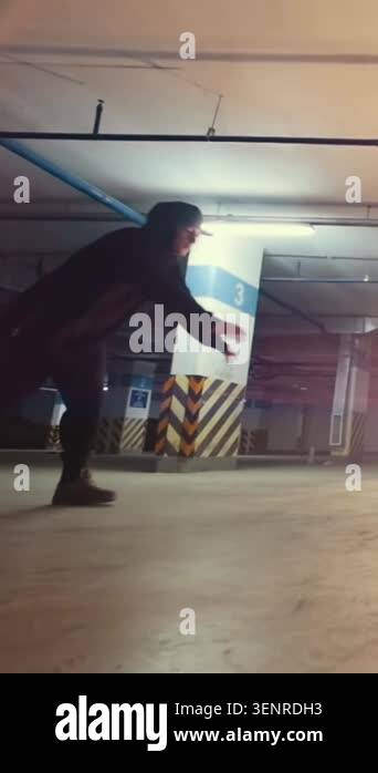 Young stylish guy reerunner doing a flip from the wall in the garage ...