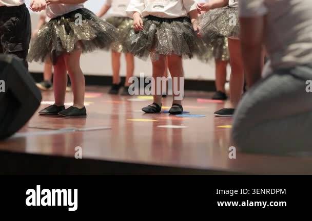 Group of kids wearing sparkly tutus and dancing during a school recital ...