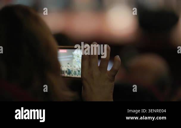 Close-up of a spectators hand holding a smartphone, capturing a ...