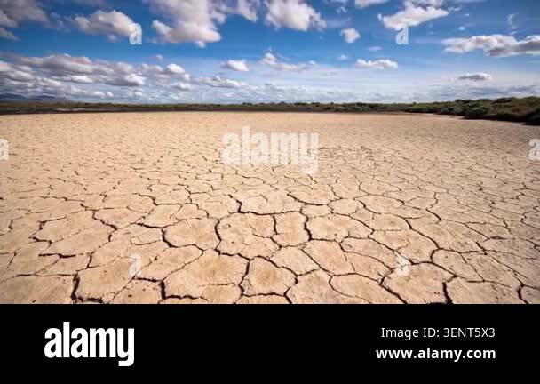 Dry cracked earth under a blue cloudy sky. Arid desert landscape, soil ...