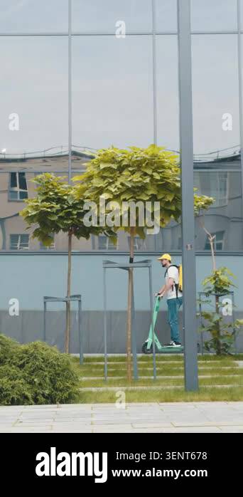 A delivery person rides an electric scooter in front of a modern ...