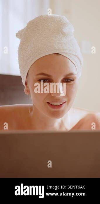 A woman wearing a towel on her head smiles and gives an okay sign while ...