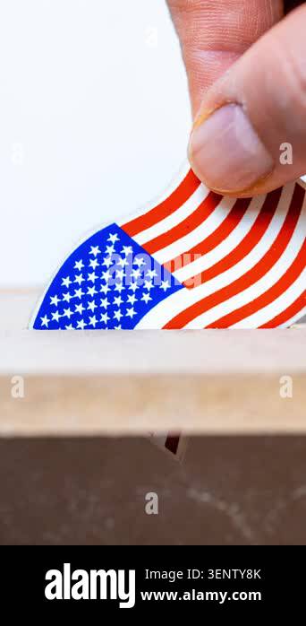 Close-up of a hand placing a American ballot token into a cardboard ...