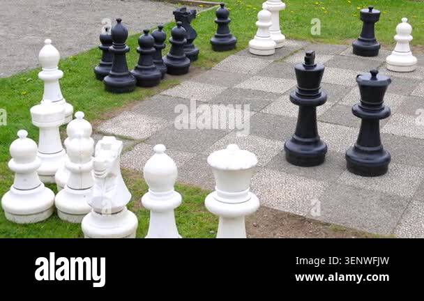 Huge chess set with large black and white pieces on a stone chessboard ...