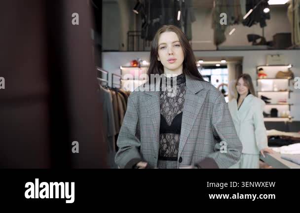 Young woman trying on a plaid blazer dress at a luxury clothing shop ...