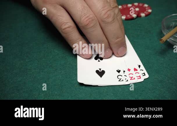 Hand positions playing cards on a green felt poker table, revealing a ...