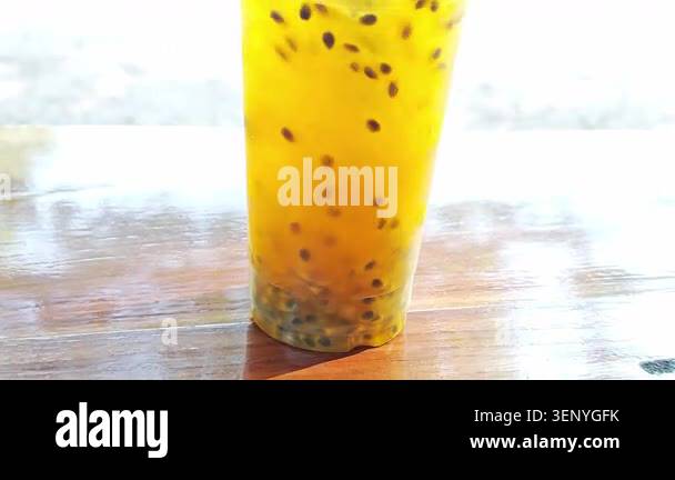Close-up of iced passion fruit juice with seeds in a plastic cup on ...