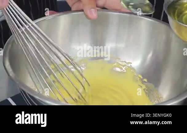 Pouring vegetable oil from a spoon into yellow batter Stock Video ...