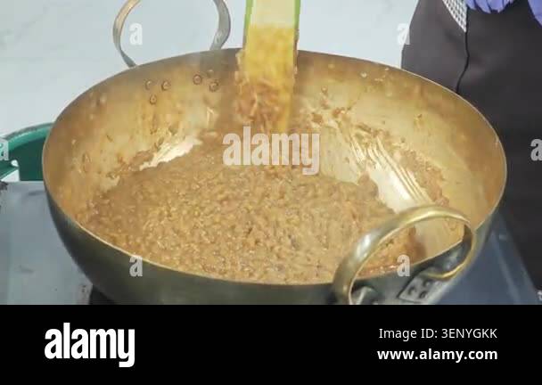 Stirring traditional Northern Thai dessert "Khanom Pad" in a brass wok ...