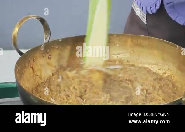 Traditional Thai dessert "Khanom Pad" being cooked in a brass wok with ...