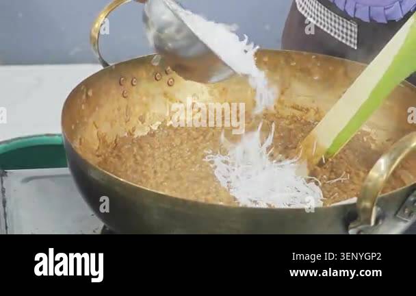 Adding shredded coconut into traditional Thai dessert "Khanom Pad" in a ...