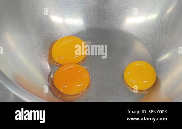 Three fresh raw egg yolks in a stainless steel mixing bowl Stock Video ...