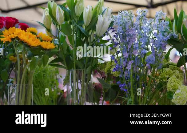 Vibrant display of fresh-cut flowers in glass vases at a farmers market ...