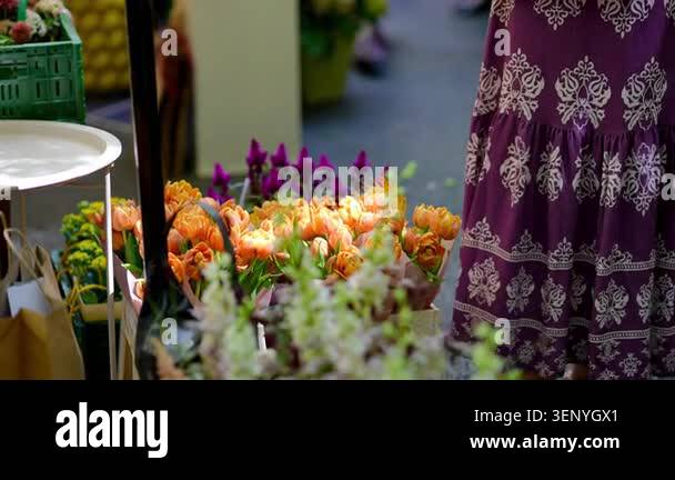 Sunny day at an outdoor flower market. Woman wearing a long skirt ...