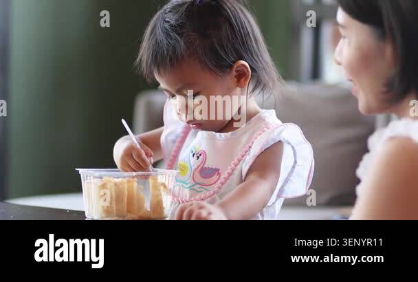 Child feeding snack independently, A little child feeds itself, while ...