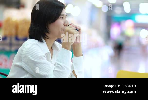 Smiling Asian woman talking on smartphone in a supermarket, food court ...