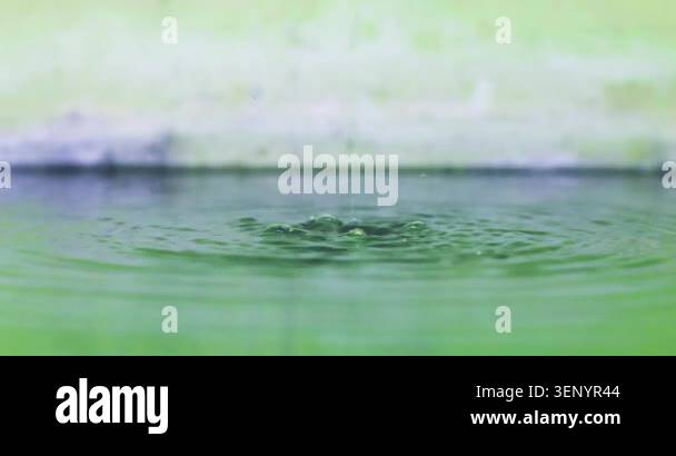Water droplet splashing on the surface, creating ripples and bubbles ...