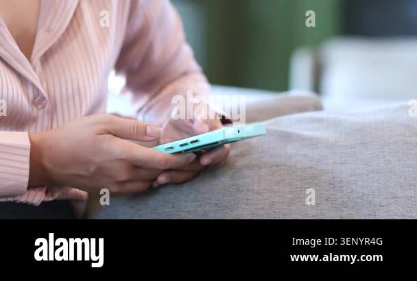Woman using smartphone while sitting on sofa at home. copy space ...
