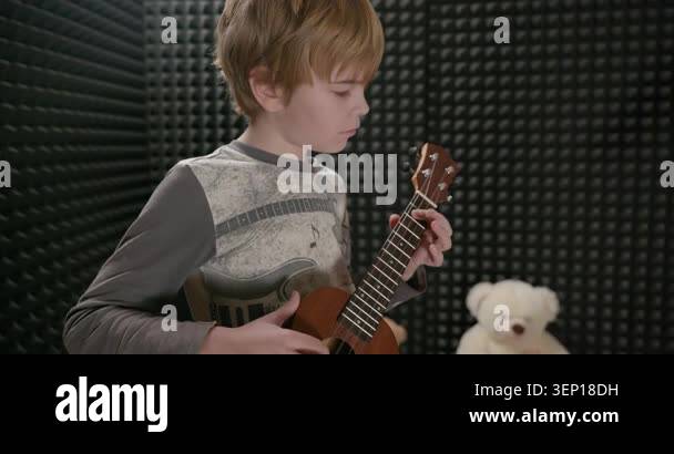 Boy Play Music on Ukulele Instrument in Home Studio. 4K 10-bit Stock ...