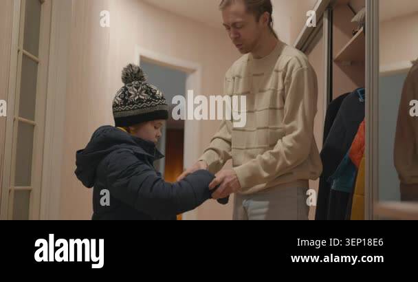Man puts warm clothes on child. Dad help child to dress at home. 4K 10 ...