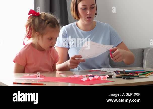 Female parent helping child create handmade cards using paints and ...