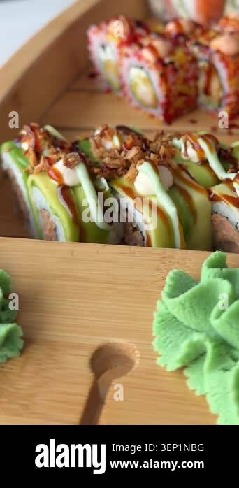 Fresh sushi rolls wrapped with avocado and topped with creamy sauce ...