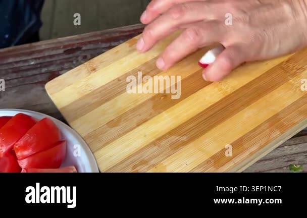 Fresh red radish cleaned and cut into pieces by female hands on rustic ...