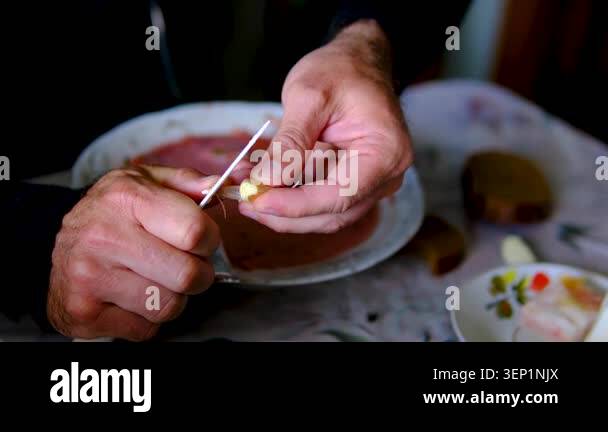 A man peels fresh garlic cloves while preparing a traditional homemade ...