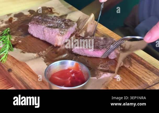 Raw beef steak sprinkled with salt from shaker on wooden board and ...
