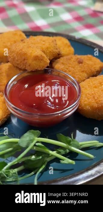 Golden crispy nuggets served on blue plate with fresh microgreens and ...