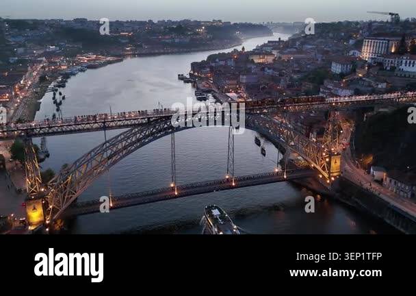 Aerial view of Portos Dom Luis I Bridge in Portugal at dusk. A metro ...