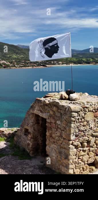 Corsican flag atop ruin. Blue Med Sea mountains. Sunny Corsica Stock ...