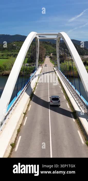 A white car drives across a white arch bridge in Corsica. The bridge ...