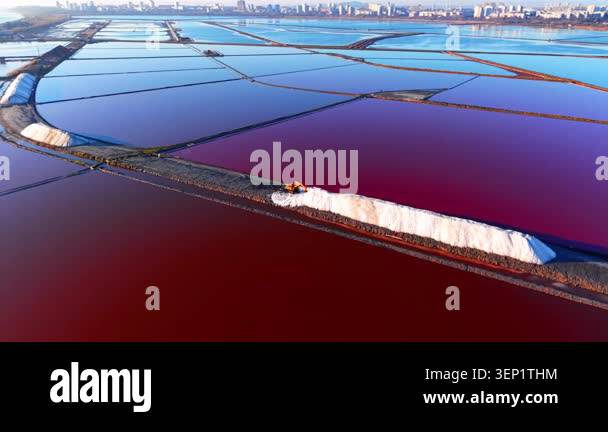 Drone view of vivid red and blue salt pans with excavator, Bulgaria ...