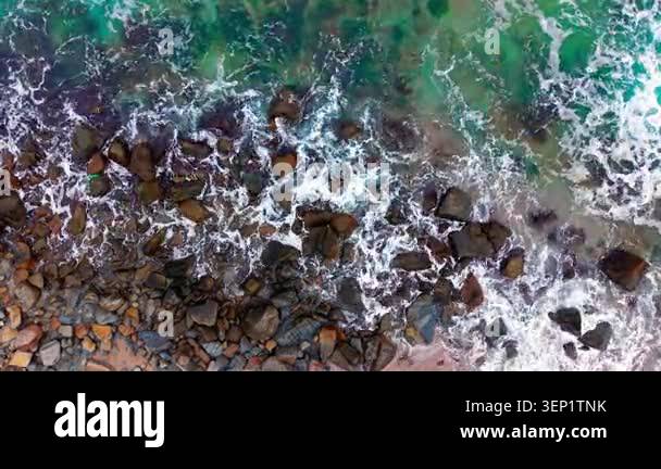Zenith drone shot of foaming turquoise water colliding with dark ...
