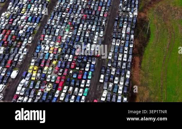 Rows of wrecked vehicles in open scrapyard beside farmland, Bulgaria ...