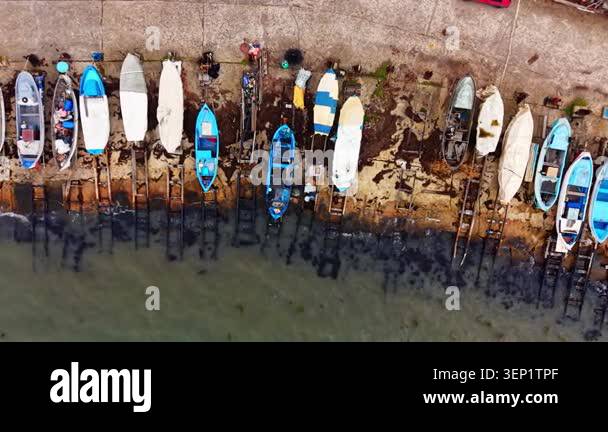 Colorful watercraft parked on wooden ramps along concrete shoreline ...