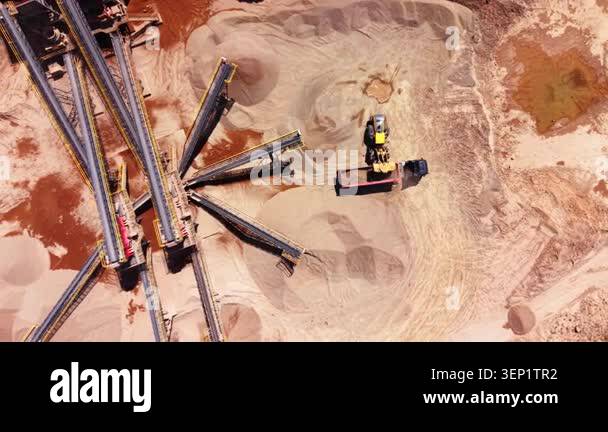 Earthmoving equipment loading mineral aggregates into a truck near ...