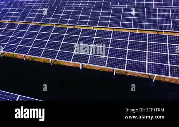 Rows of dark silicon modules casting shadows onto the soil. Industrial ...