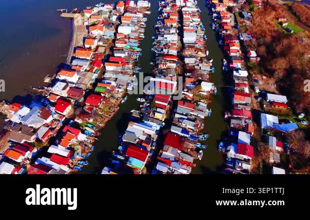 Narrow waterways flanked by dense residential huts. Top-down drone view ...