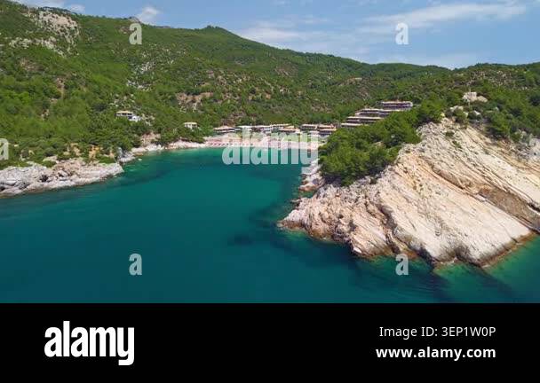 Aerial view of a circular bay with emerald water, a sandy beach, and ...