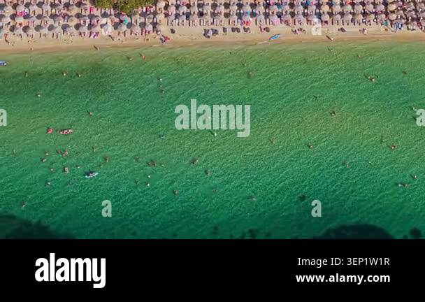 Aerial view of many tourists relaxing under umbrellas on a sandy beach ...