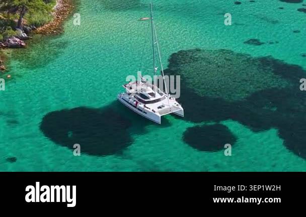 Aerial view of a white catamaran sailing in turquoise water near a ...