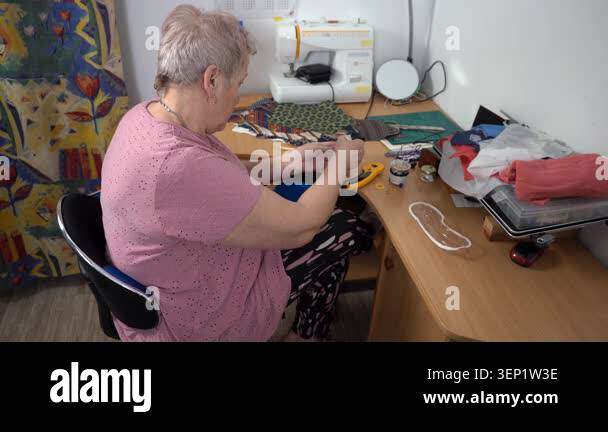 Replacing the blade for a knife for cutting fabric. An elderly woman is ...