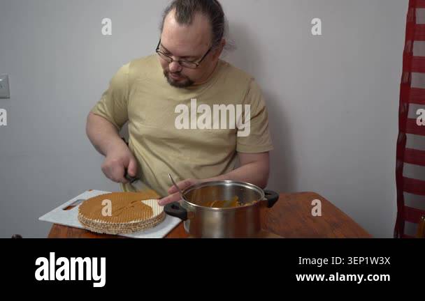 Man spread wafer cakes with condensed milk. Simple cake. Sweet food at ...