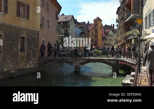 Tourists walking across a small bridge over a canal in old town Annecy ...