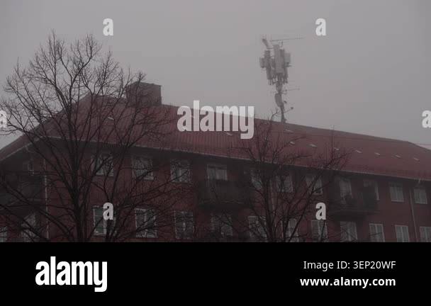 Communication antenna on residential building roof in foggy weather ...