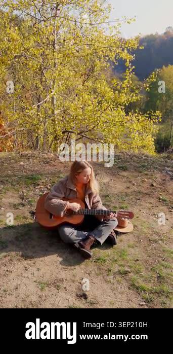 Blonde woman playing string guitar outdoors in autumn forest. Concept ...